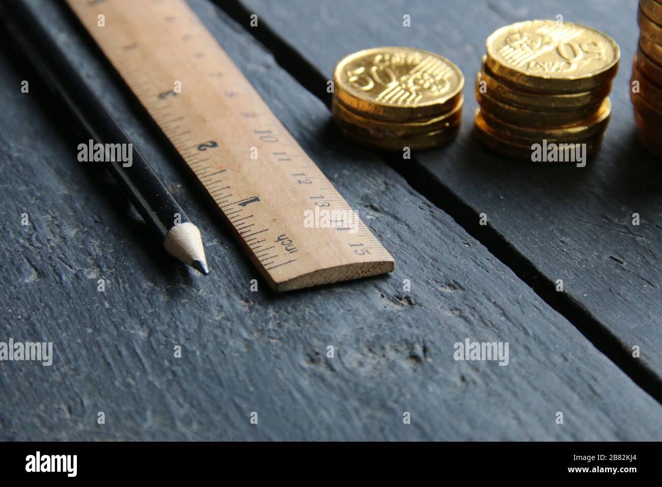 Piles of gold coins, a pencil and a ruler on the table Stock Photo - Alamy