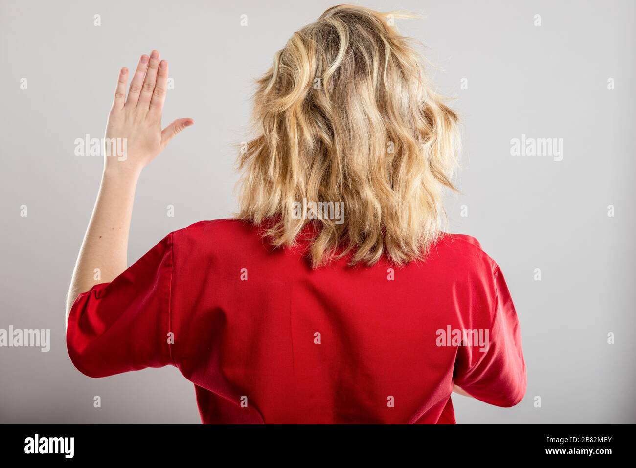 Back view of female nurse wearing red scrub taking oath gesture on ...
