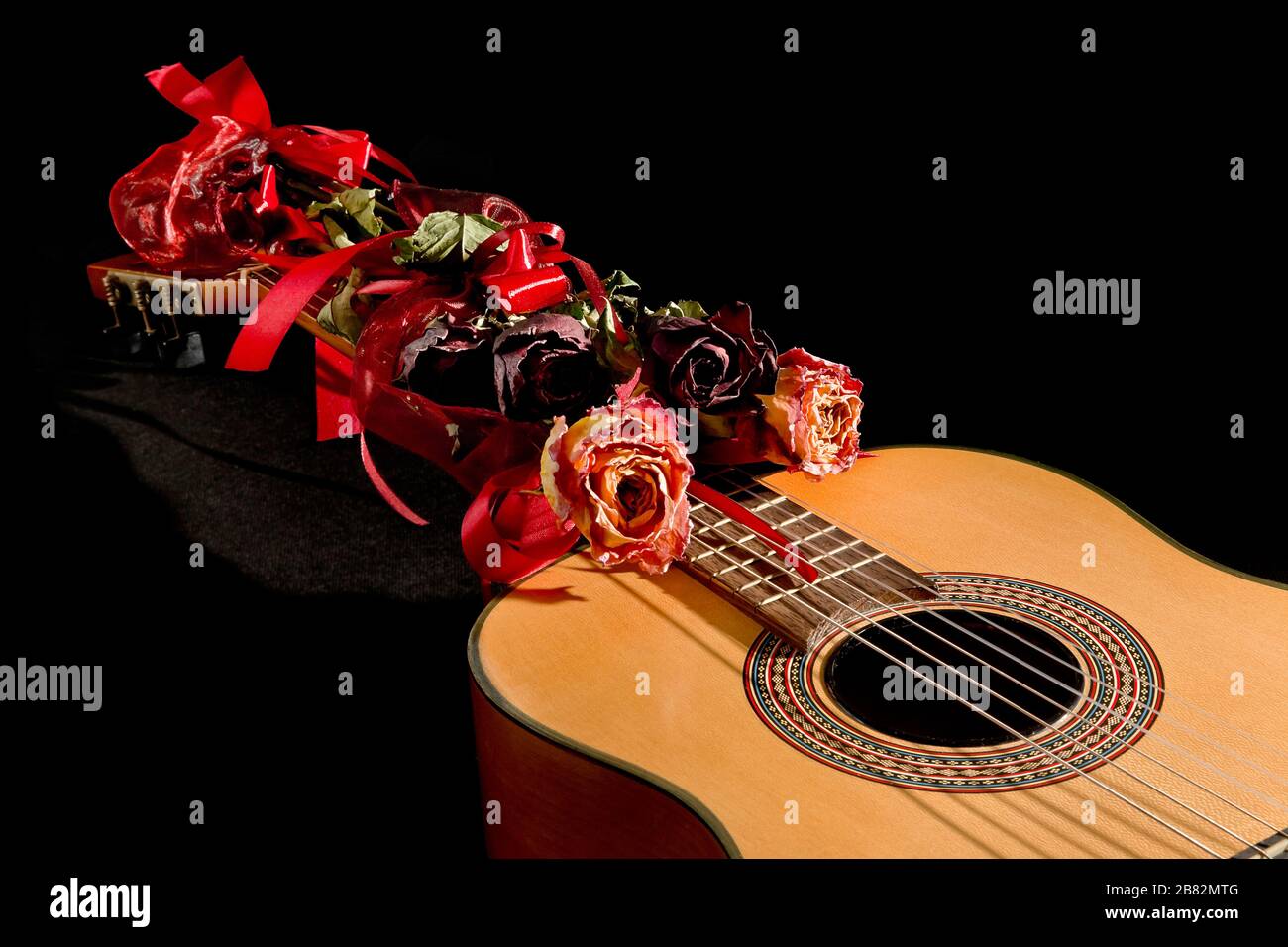 Acoustic guitar and dried roses on black background Acoustic guitar and ...