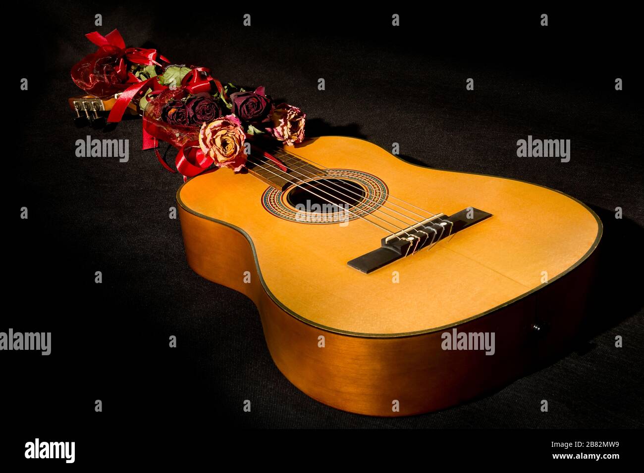 Acoustic guitar and dried roses on black background Acoustic guitar and ...