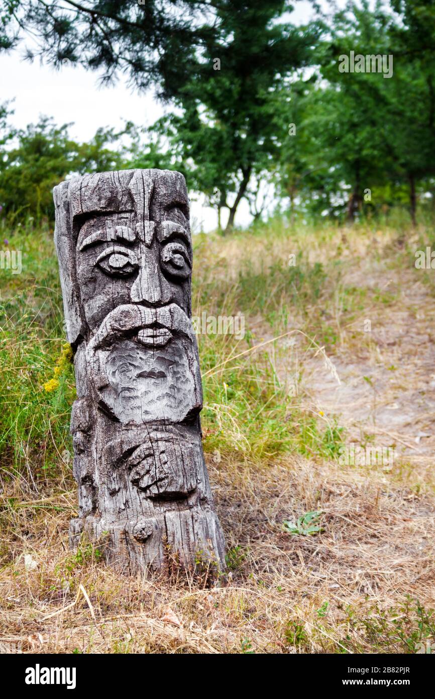 Wooden idol of Slavic god by a path in the forest. Forest in the ...