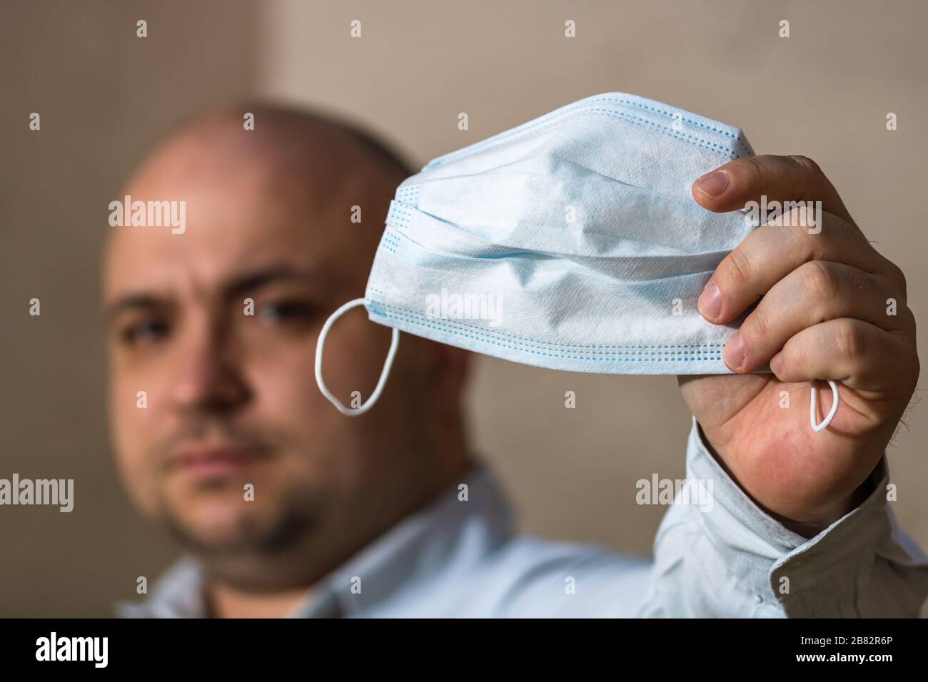 Caucasian young man holding medical face mask to prevent virus disease ...