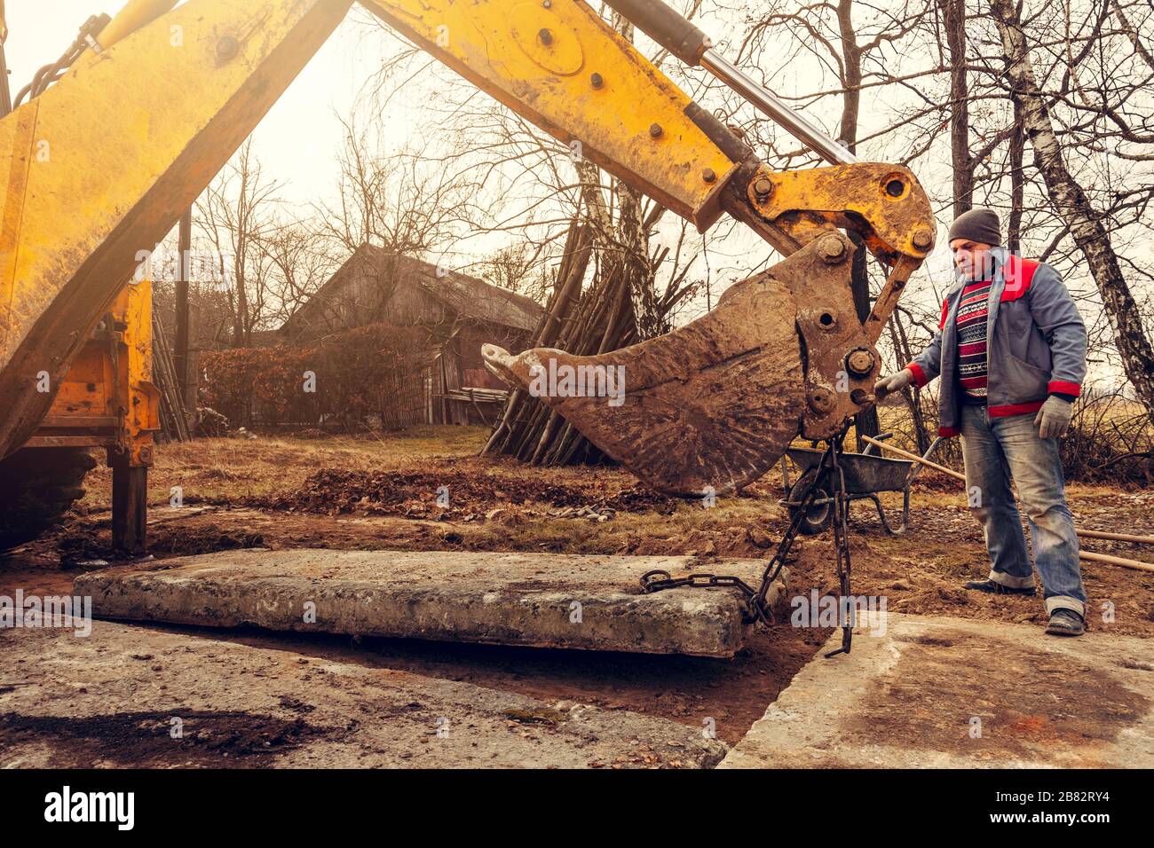 The worker clings the chain to the excavator bucket to raise the ...