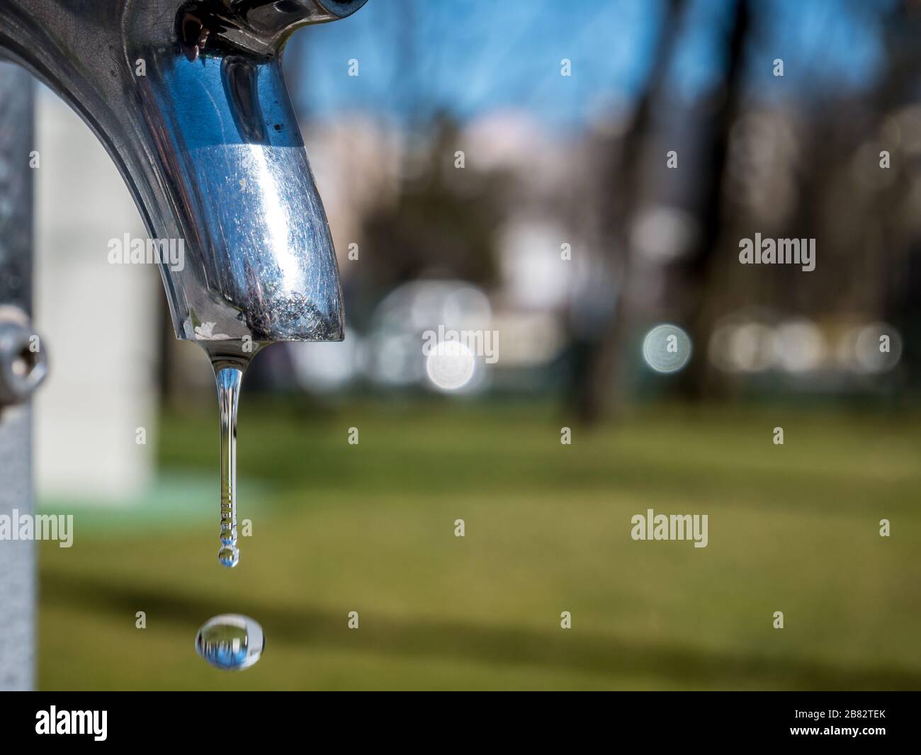 Water dripping from a water tap. Drop of water close up with a blurred ...