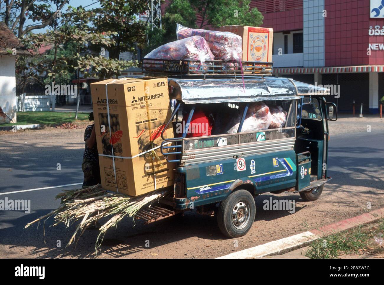 A Jumbo - a large Tuk-Tuk - being loaded with bamboo, a refrigerator ...
