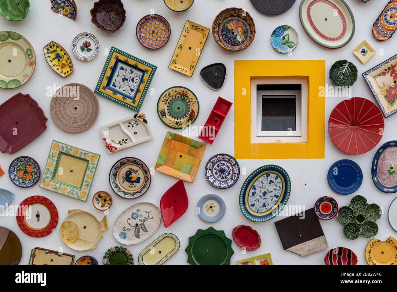 Hand painted ceramics on a house wall with small window hi-res stock ...