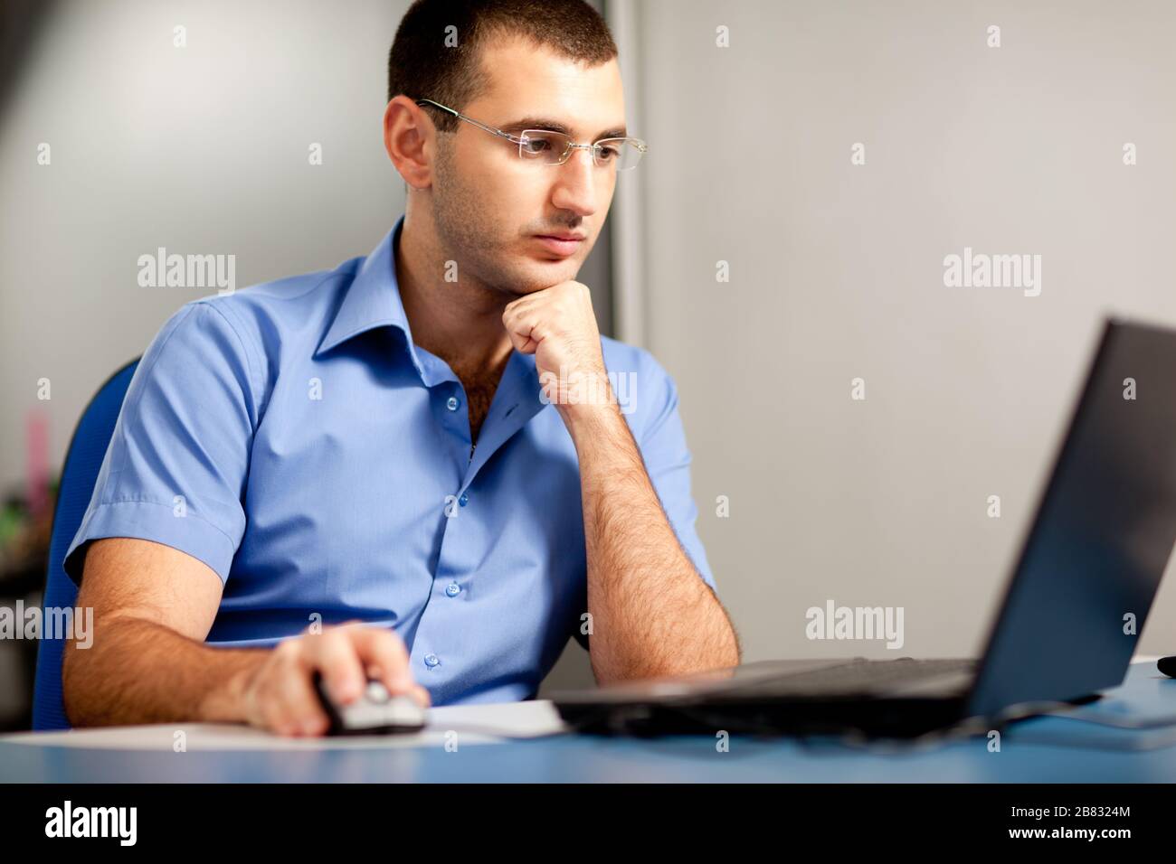 Young policeman in uniform and glasses sitting in office and working at ...
