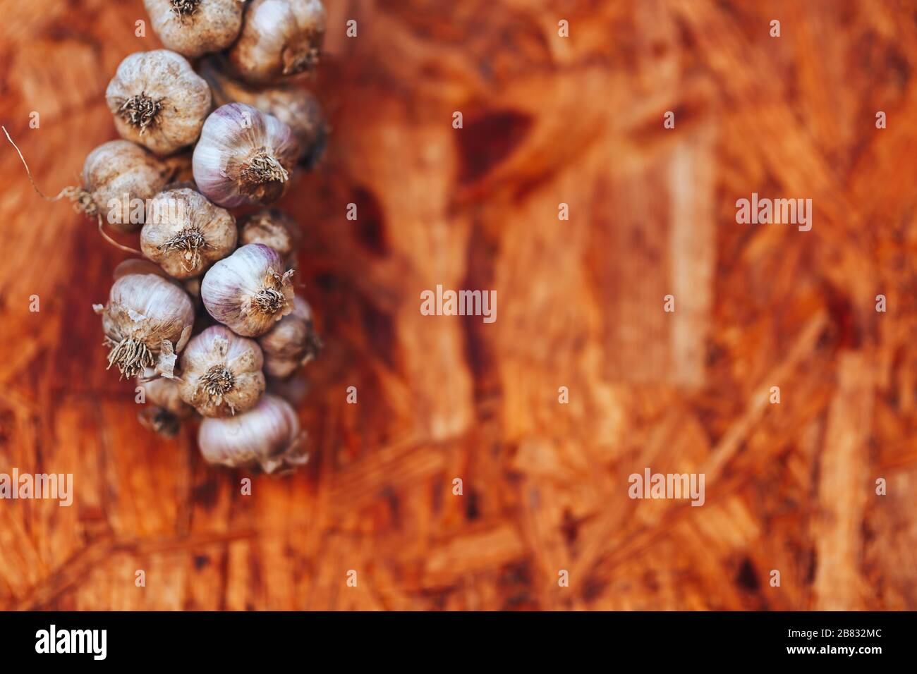 garlic pigtail on wooden background hanging in corner Stock Photo - Alamy