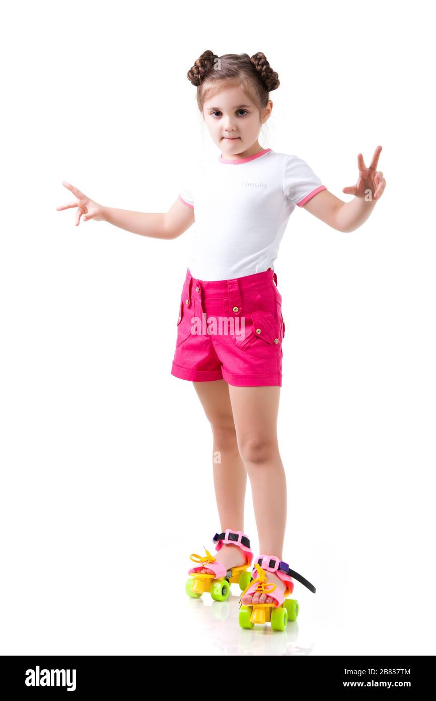 Small positive girl in stylish clothing standing on rollers and smiling ...