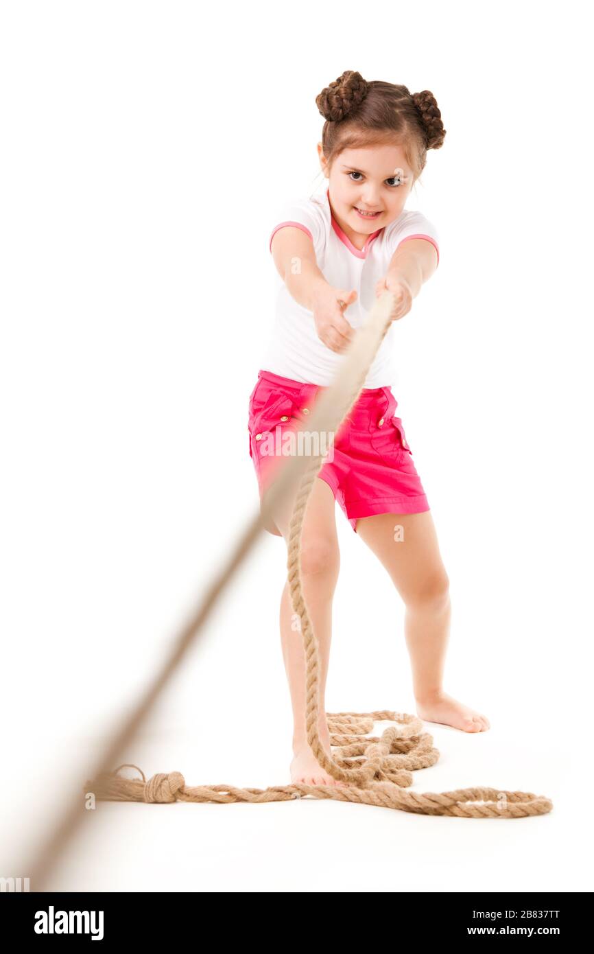 Small positive girl in stylish clothing standing, playing in pulling ...