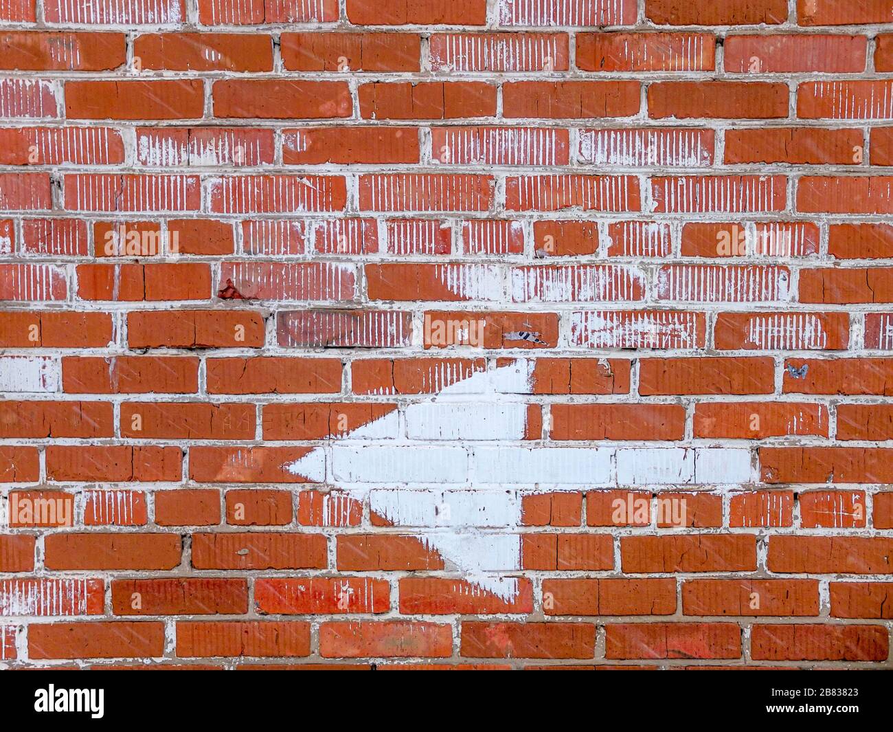 An old red brick wall with traces of white paint and a large white ...