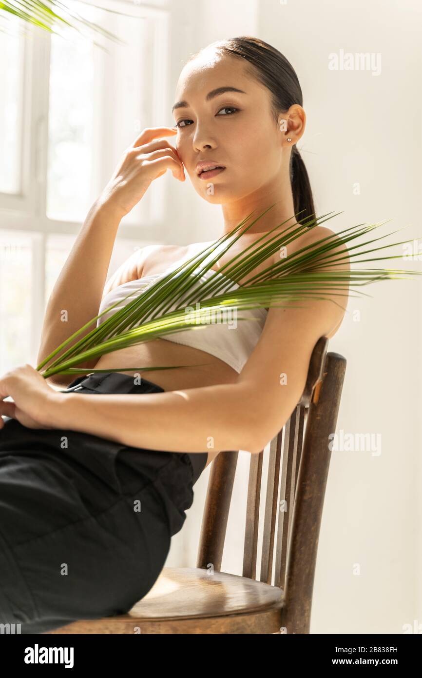 Beautiful lady resting with palm leaf in room Stock Photo - Alamy