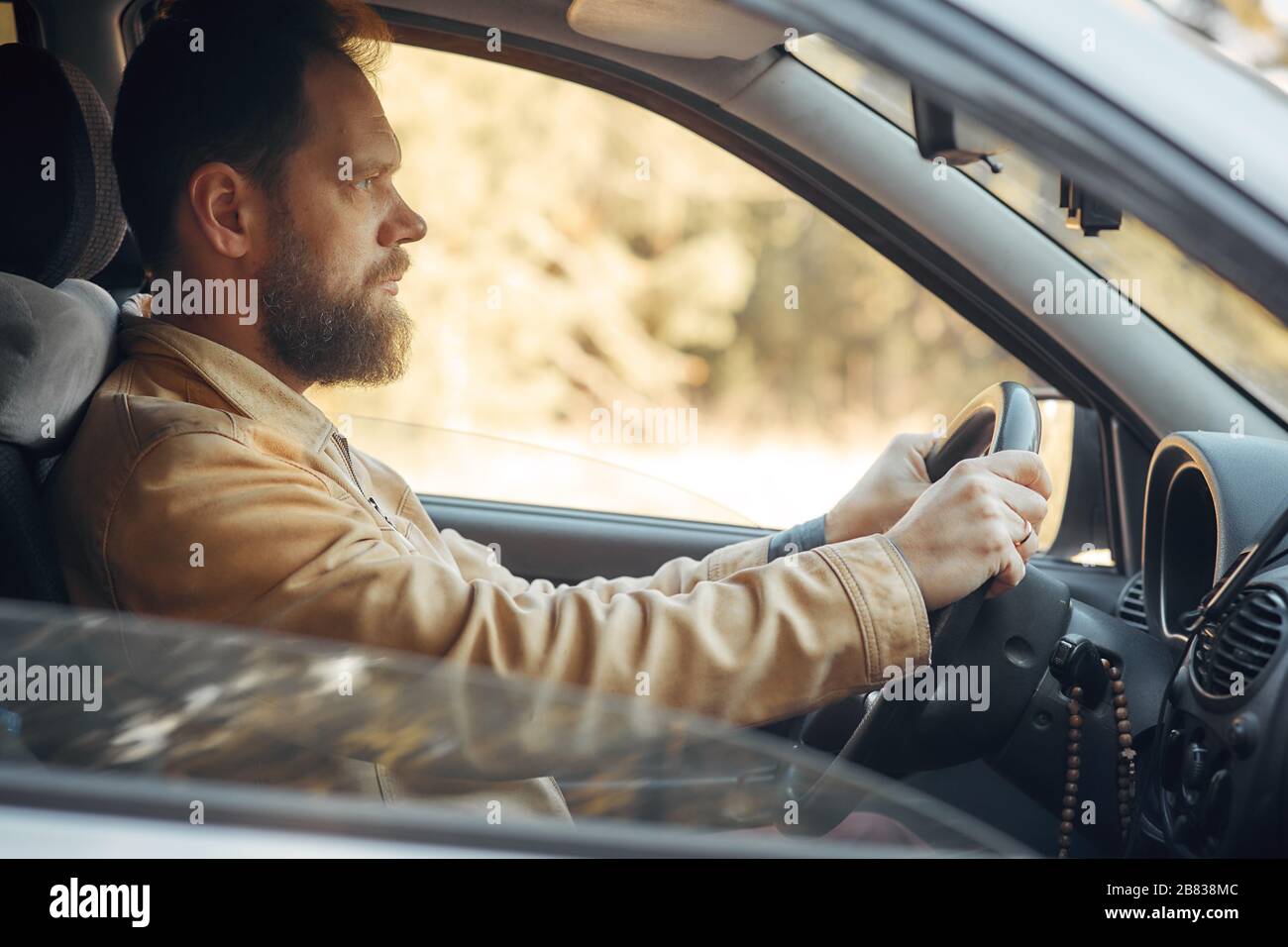 a man with a beard driving a car Stock Photo - Alamy