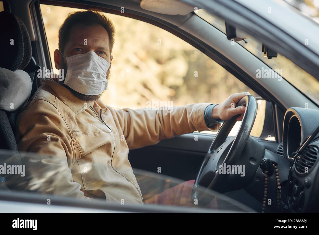a man driving a car puts on a medical mask during an epidemic, a taxi ...