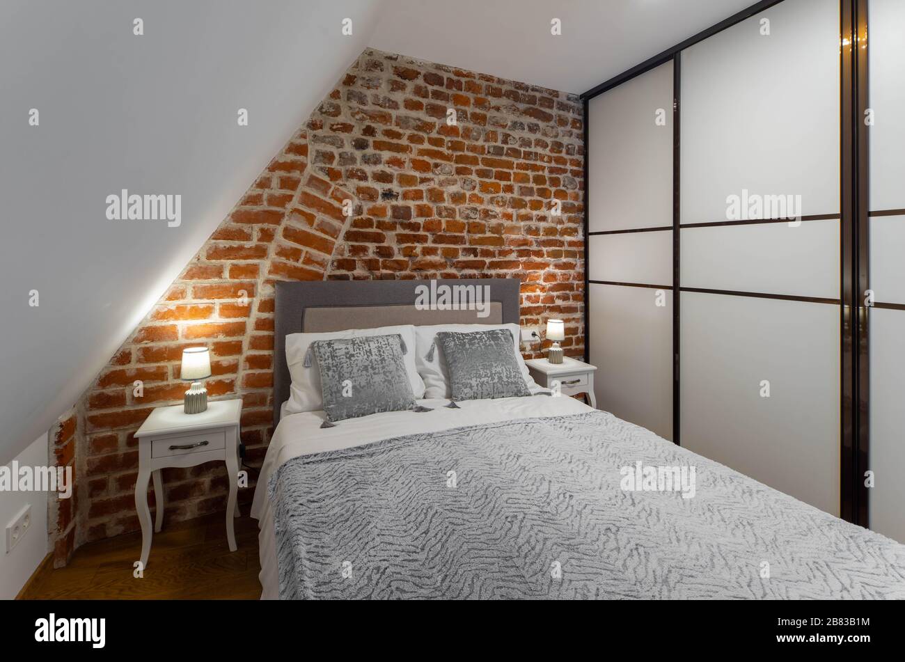 Modern loft interior of cozy bedroom. Brick wall and sloping ceiling ...