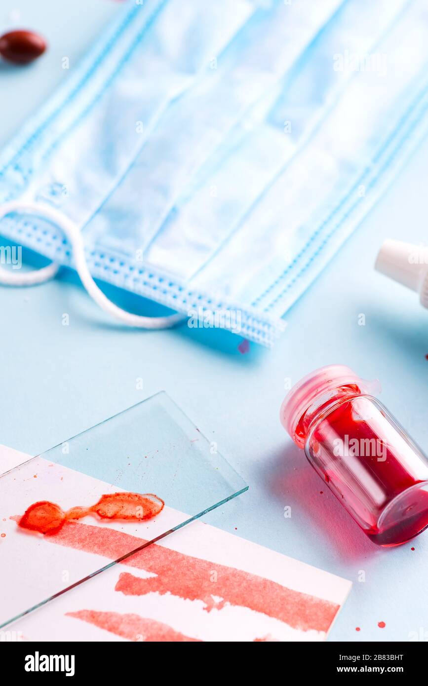 Glass bottle with red blood or liquid and disposable protected mask on ...