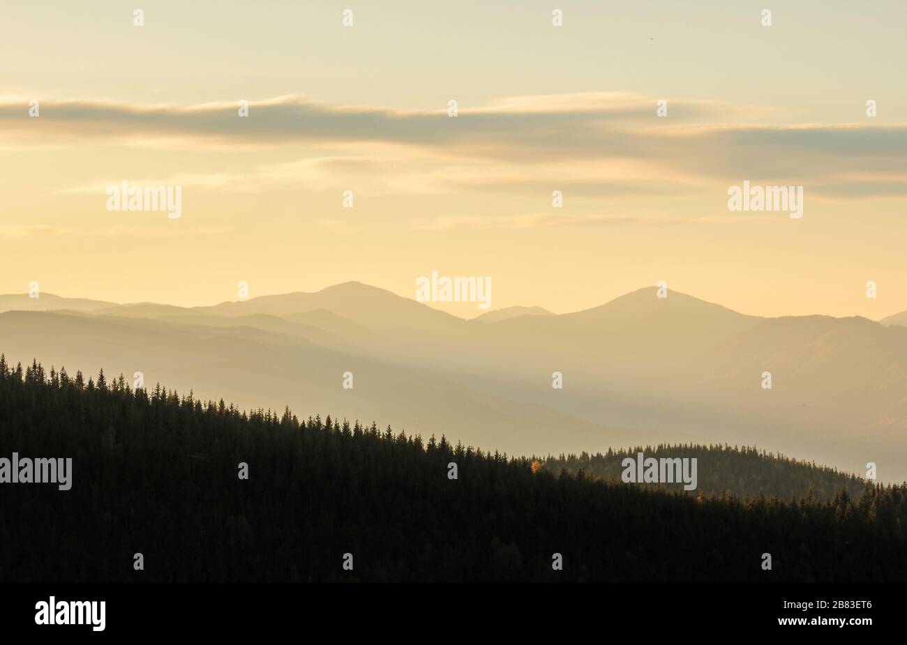 Warm gradient of dawn sky above layers of mountain and rock silhouettes ...