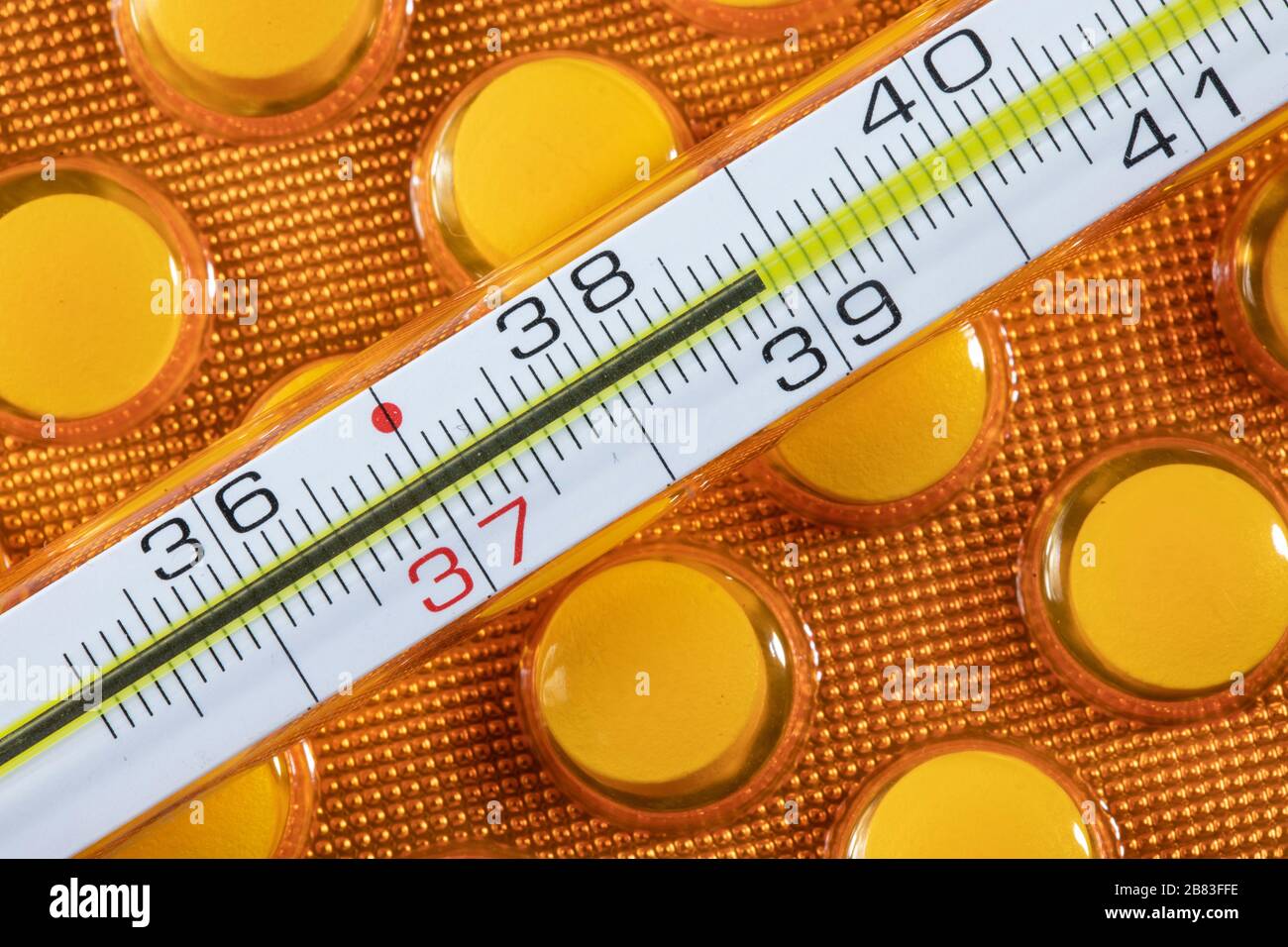 Clinical thermometer indicating fever 39C, and a group of pills, drugs ...