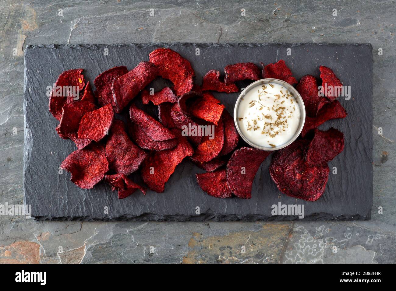 Healthy beet chips with dip, above view on a stone server and slate ...