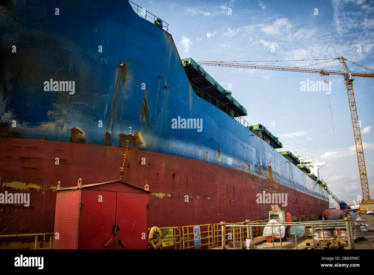 A large tanker cargo ship is being renovated and painted in shipyard ...