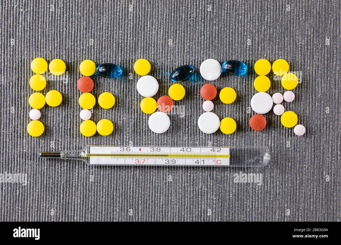 Word "Fever" made out of pills, drugs. Clinical termometer indicating ...
