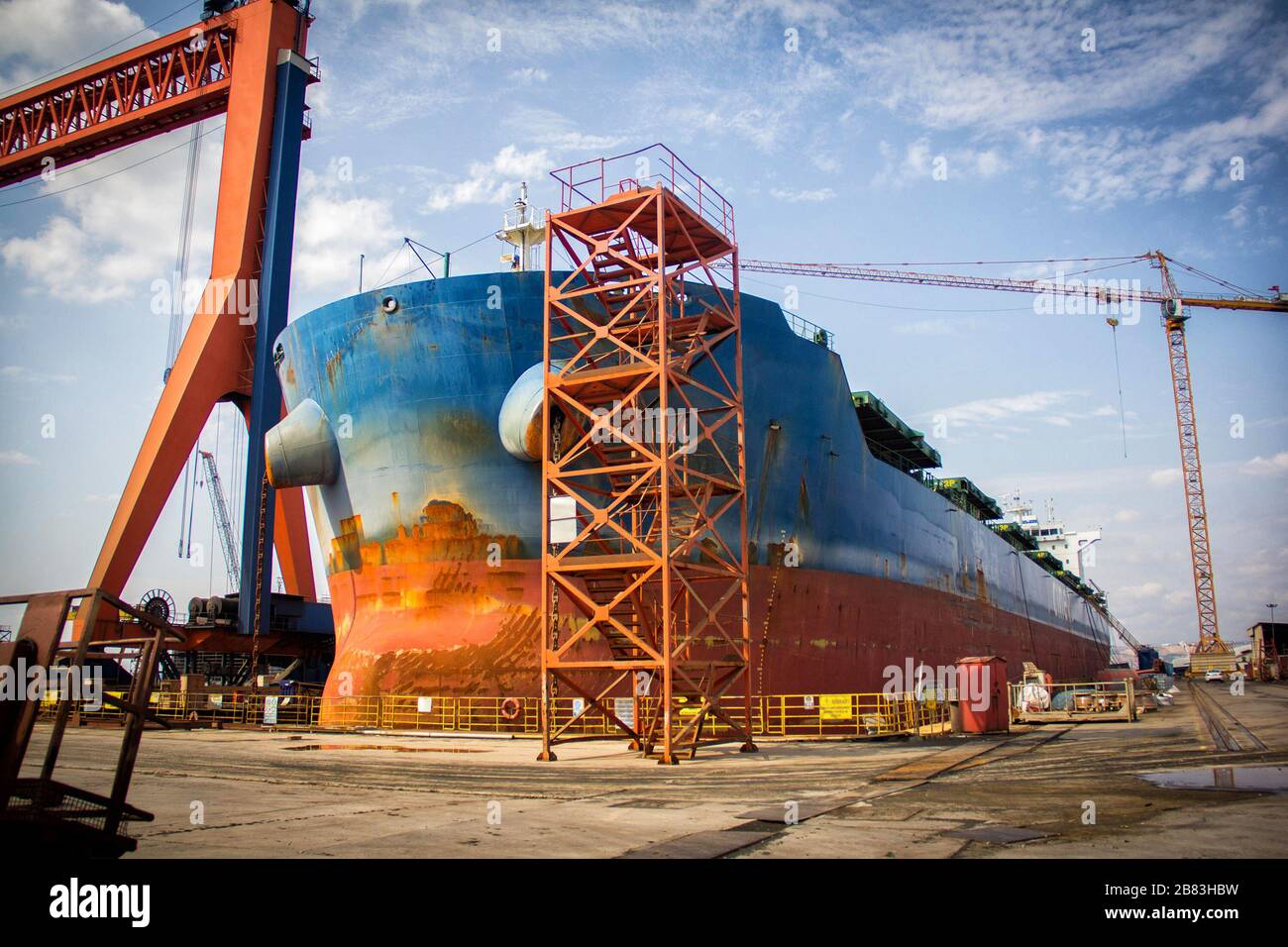 A large tanker cargo ship is being renovated and painted in shipyard ...