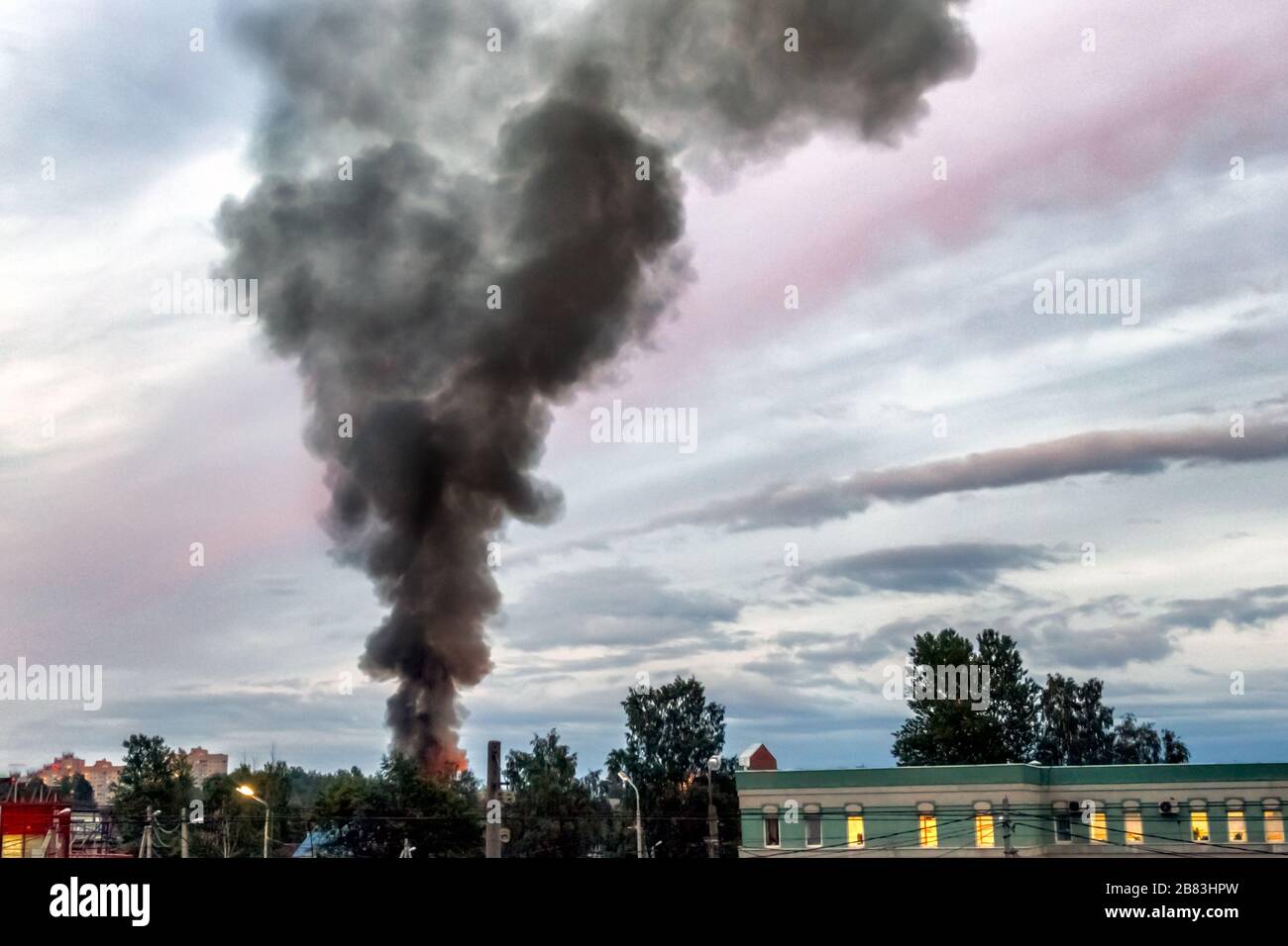 the building burns with fire and black smoke against the evening sky ...