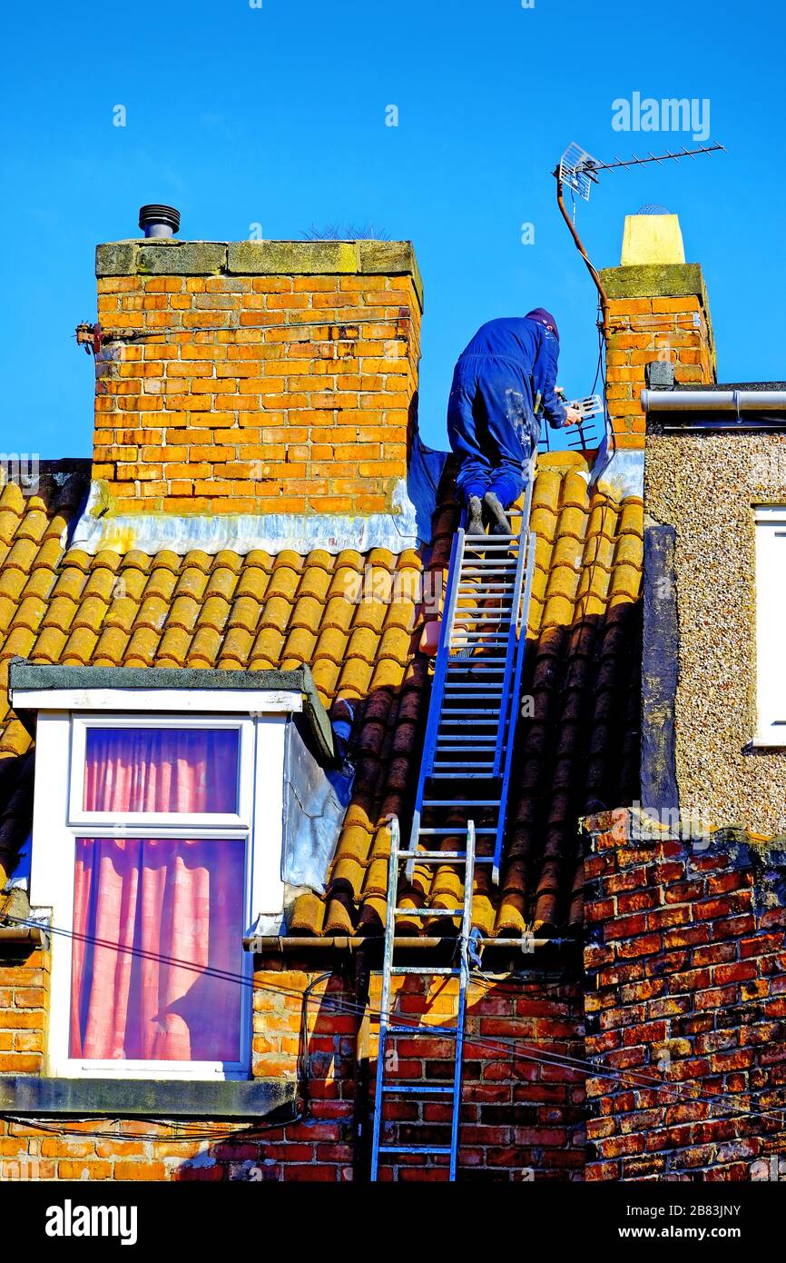 TV aerial fitter on roof ladders Stock Photo - Alamy