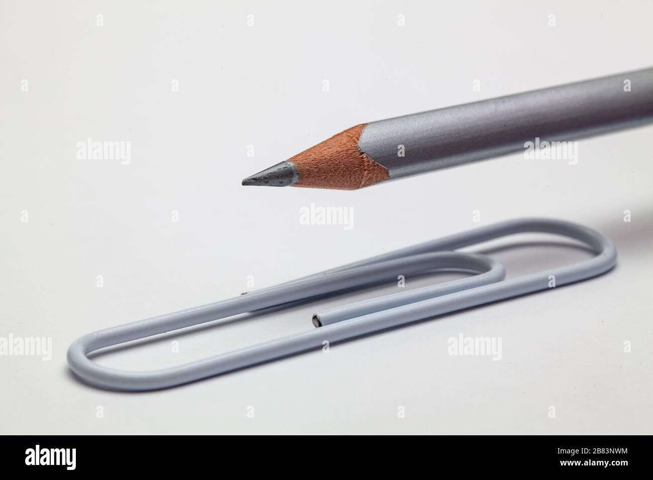 Levitating silver color pencil and paperclip on the white office table ...