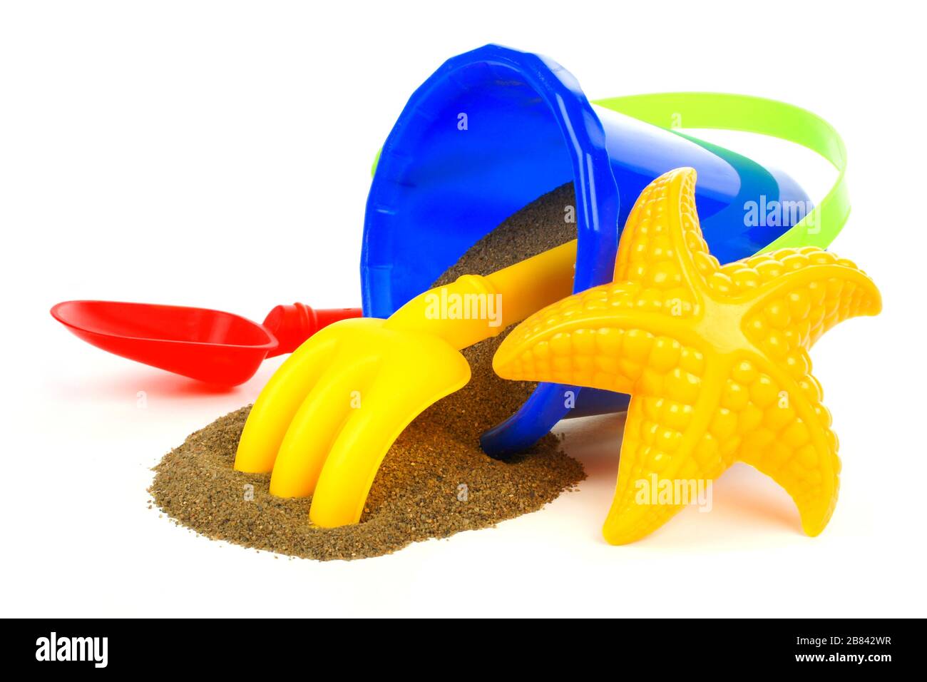 Spilling toy sand pail with rake, shovel and starfish isolated on a ...
