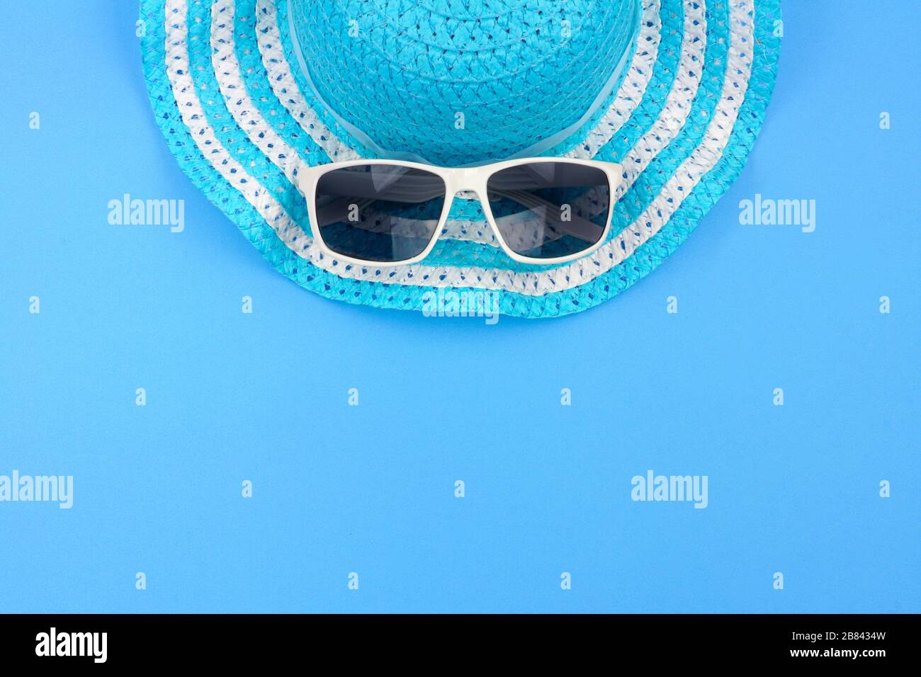 Summer hat with sunglasses. Top view, minimal concept over a blue ...