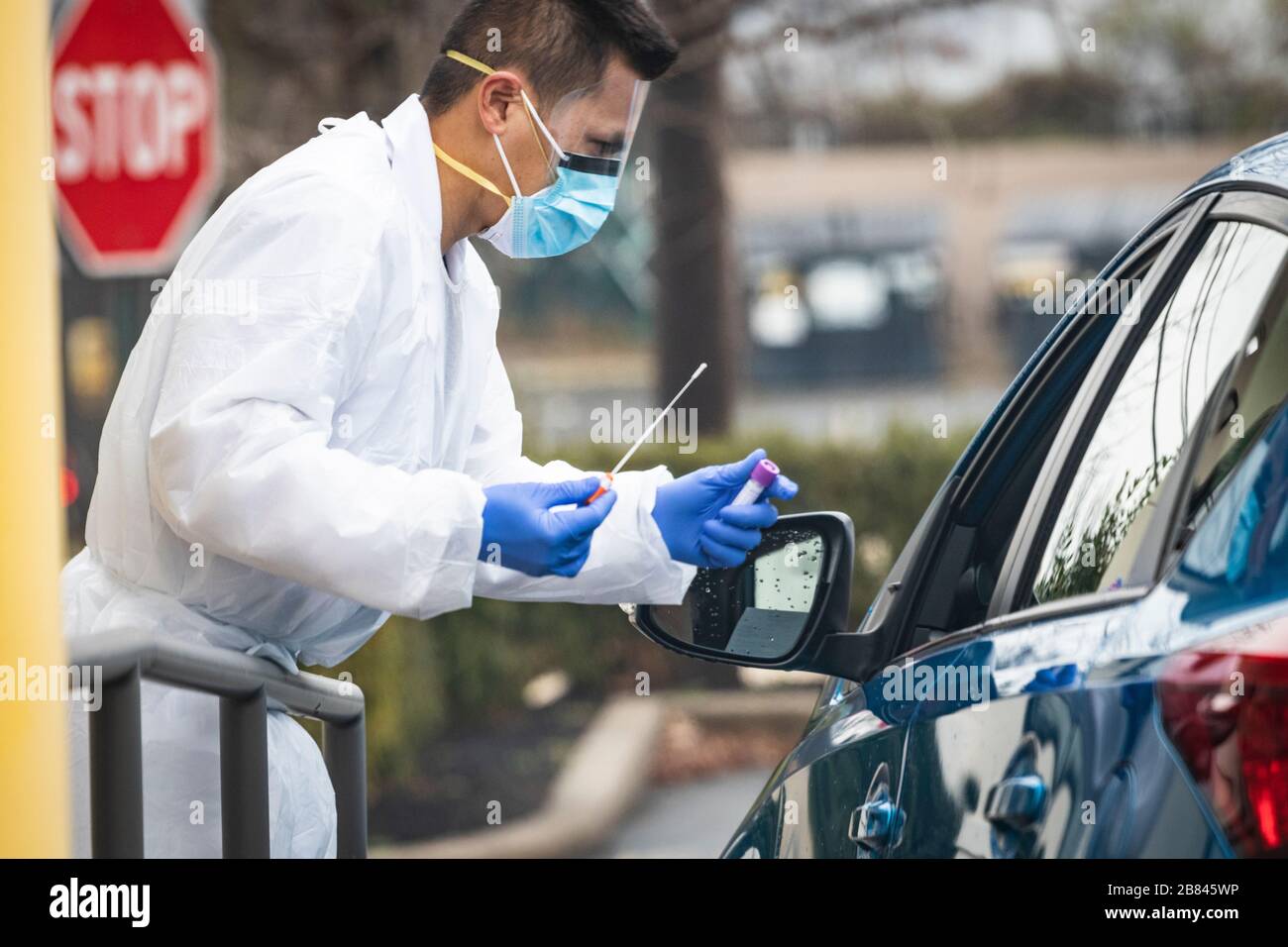 Healthcare worker administers COVID-19 test to patients in drive-thru ...