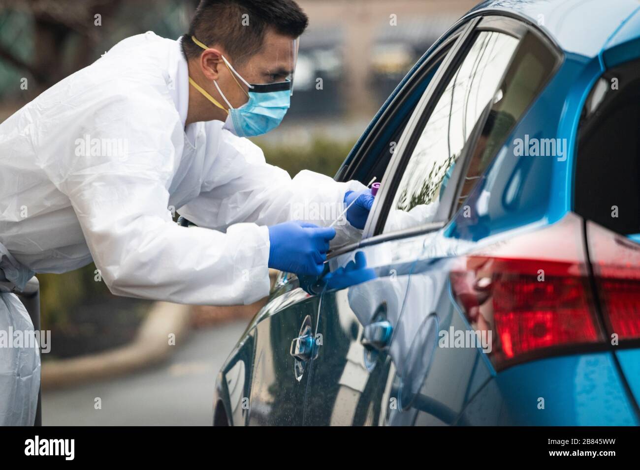 Healthcare worker administers COVID-19 test to patients in drive-thru ...