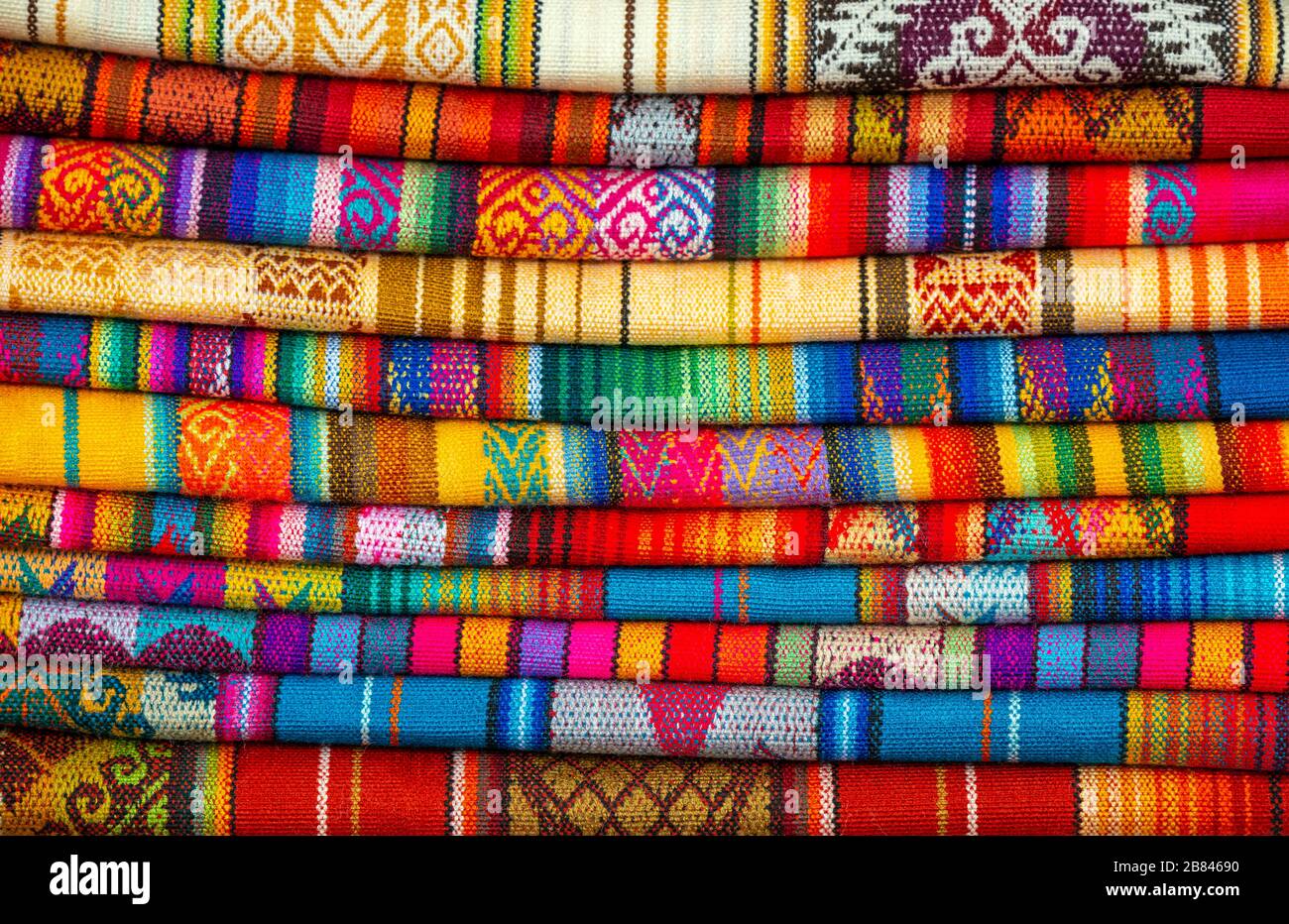 A horizontal stack of colorful Andes fabrics on the sunday market of ...