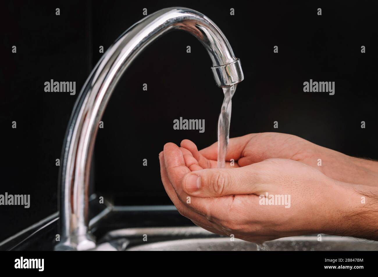 hands of a man drinking some water flowing through her fingers ...