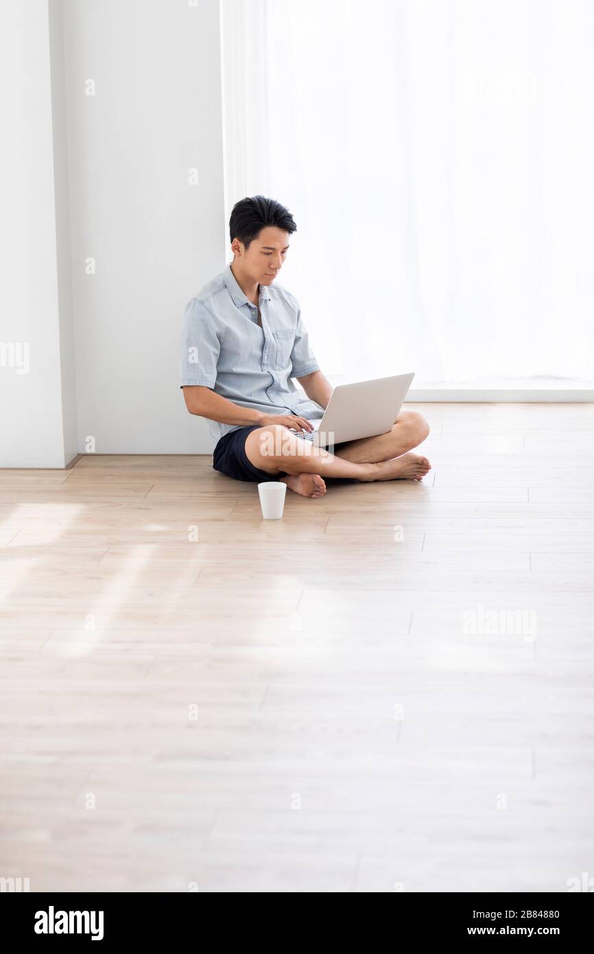 Young Chinese man using laptop on floor Stock Photo - Alamy