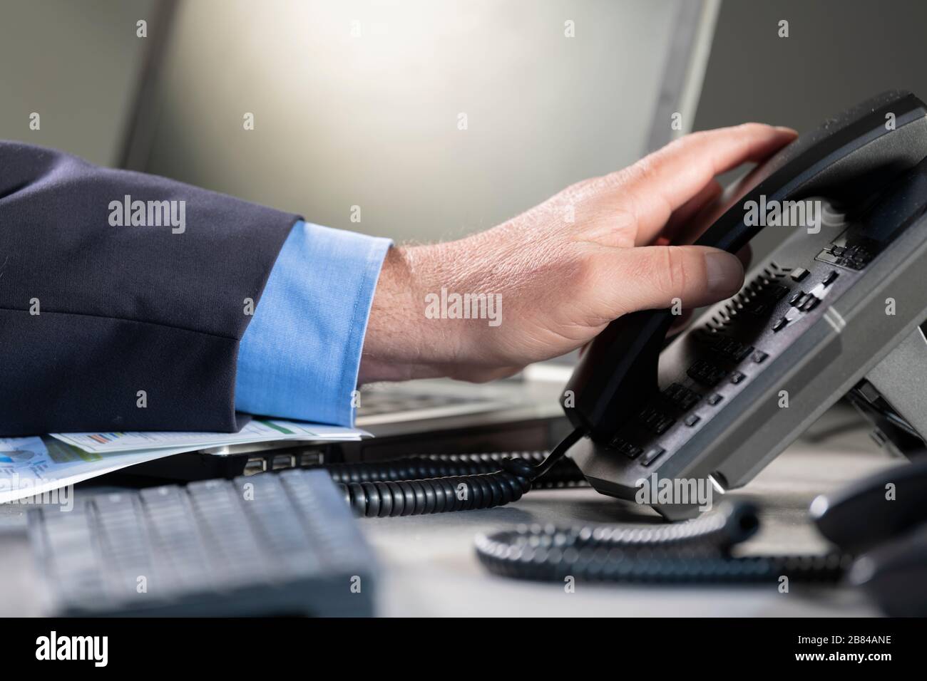Male hand picking up telephone at an office Stock Photo - Alamy
