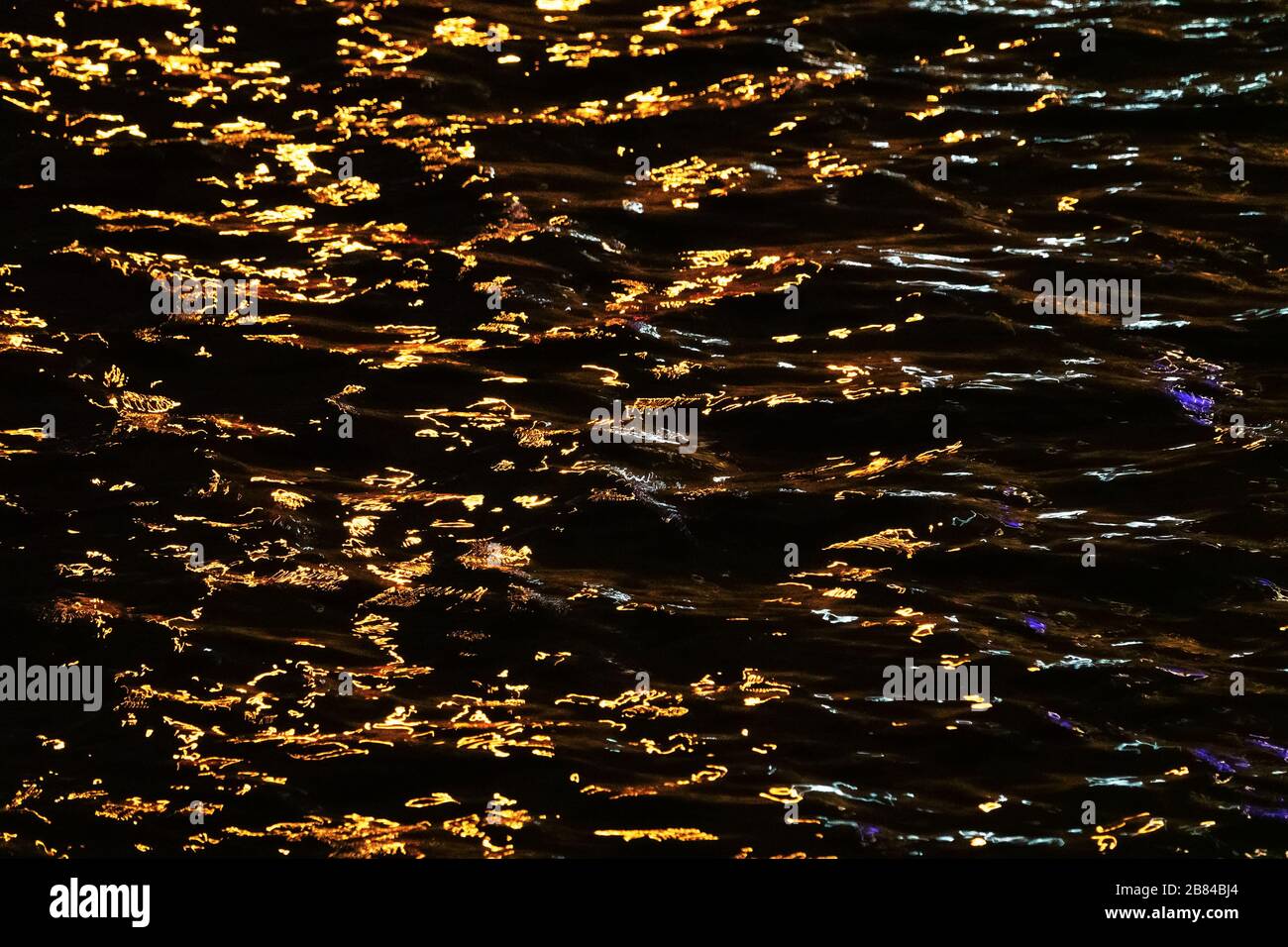 Water surface. The oily sheen of the night waves in the lamplight. Oil ...