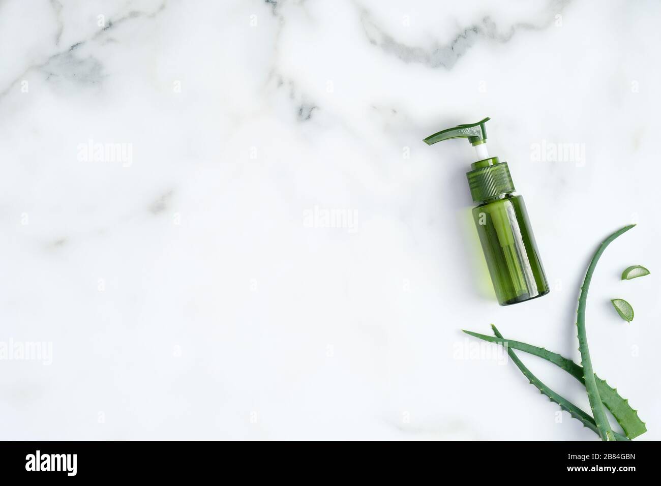 Aloe vera moisturizing gel bottle and sliced plant stems on marble ...