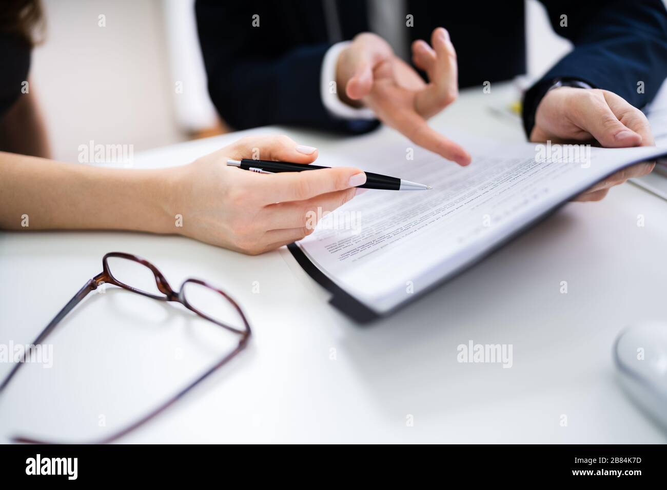 Two Businesspeople Hand Analyzing Document Over Glass Desk Stock Photo ...