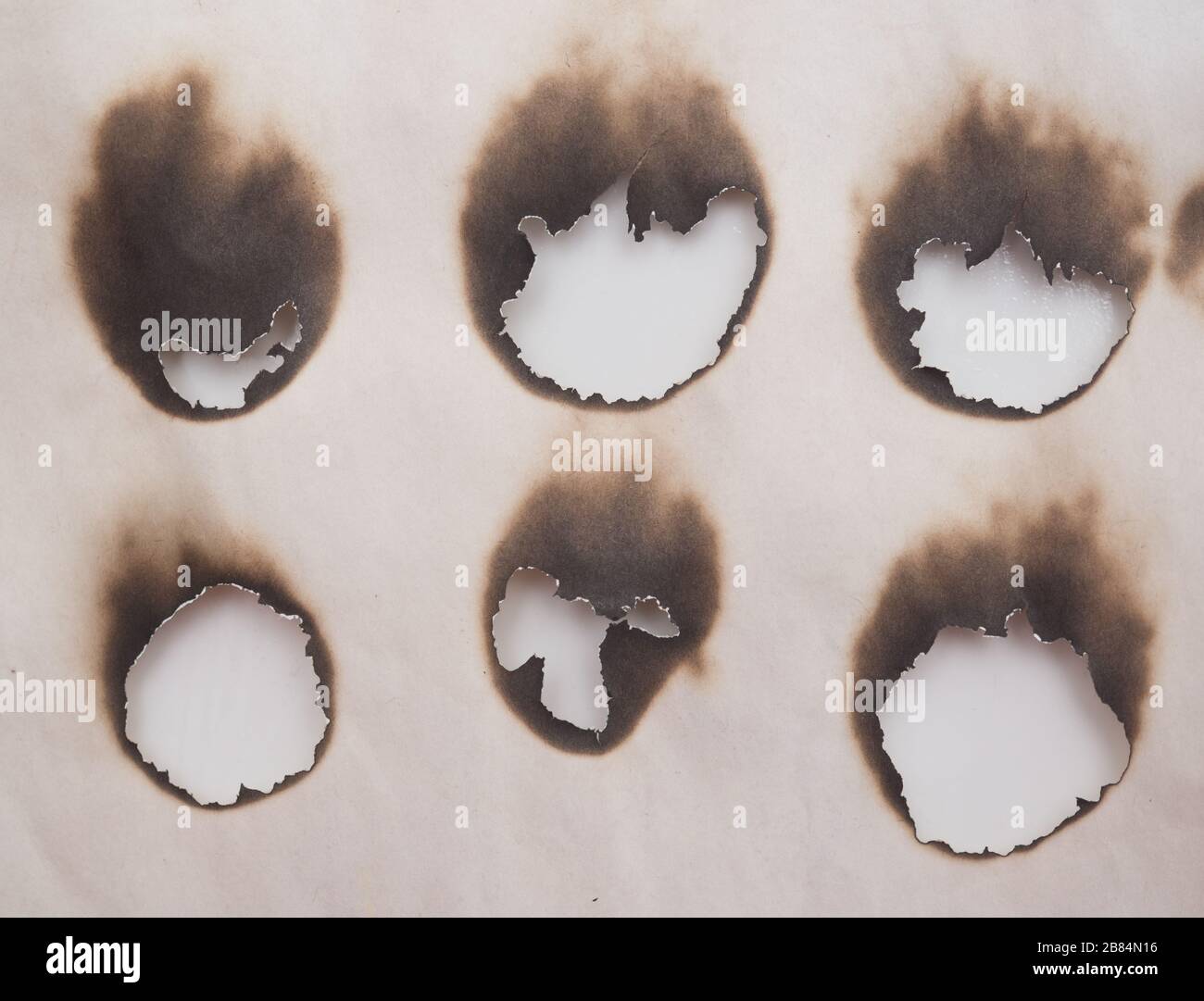 Burnt holes in a paper Stock Photo - Alamy