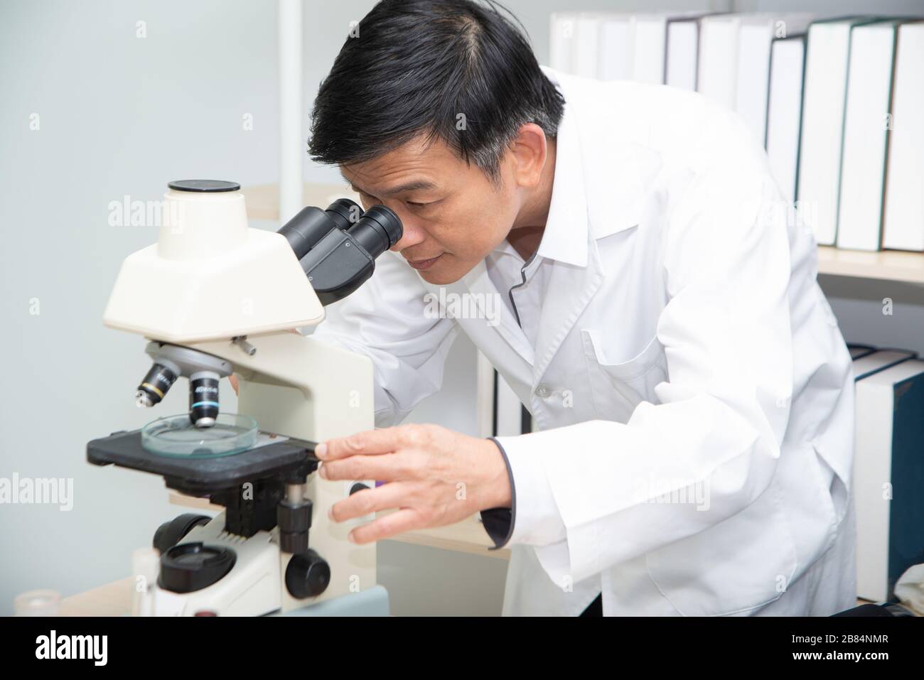 Scientist using Microscope in Laboratory. Male Researcher wearing white ...