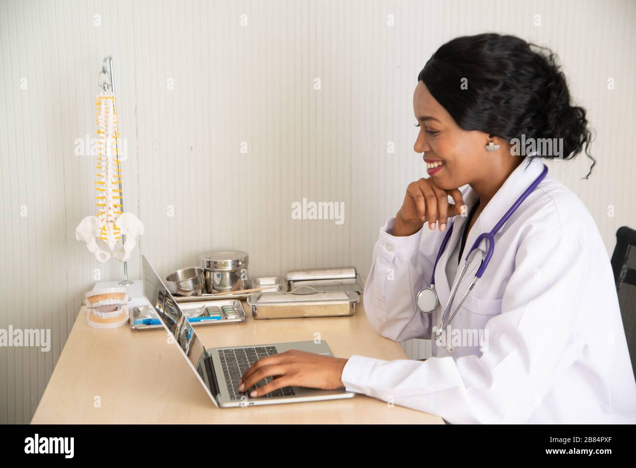 African female Doctor typing on laptop computer while sitting at the ...