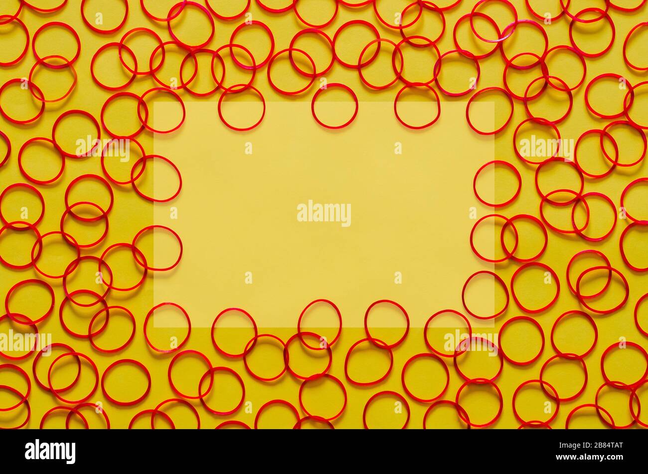 Red color elastic rubber bands put on yellow background with empty ...