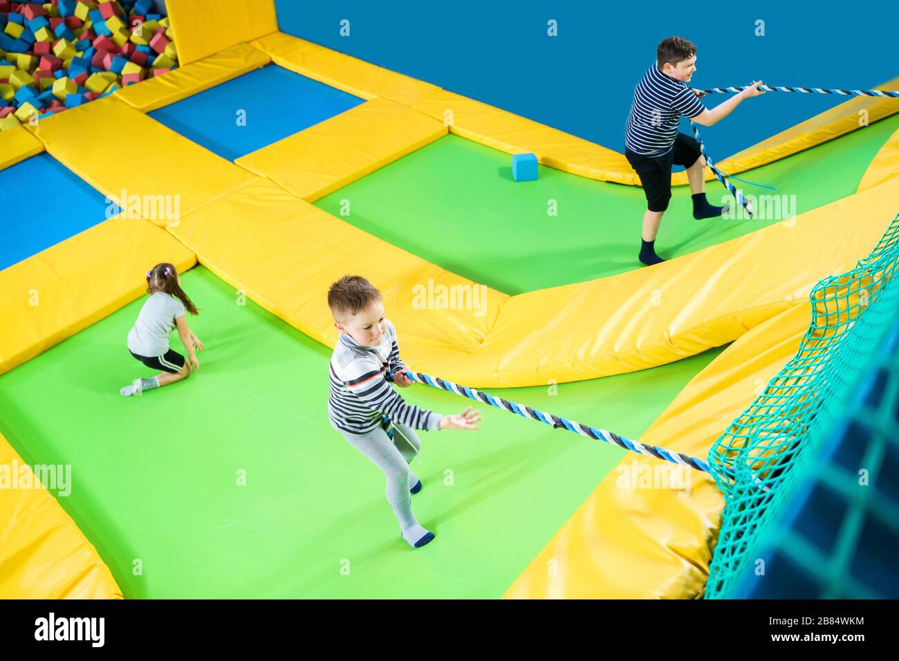 Kids playing in trampoline center jumping and climbing with rope Stock ...
