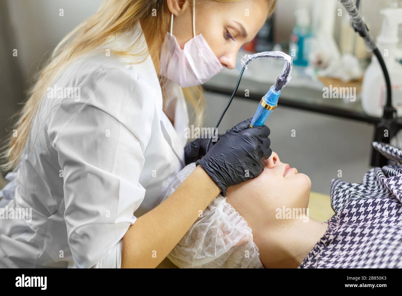 Microblading eyebrows work flow in a beauty salon. Woman having her eye ...