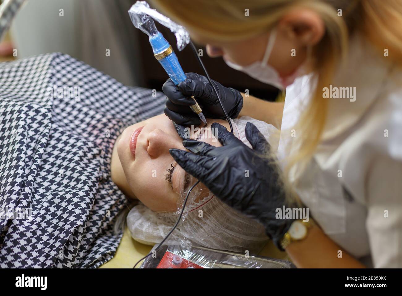 Microblading eyebrows work flow in a beauty salon. Woman having her eye ...