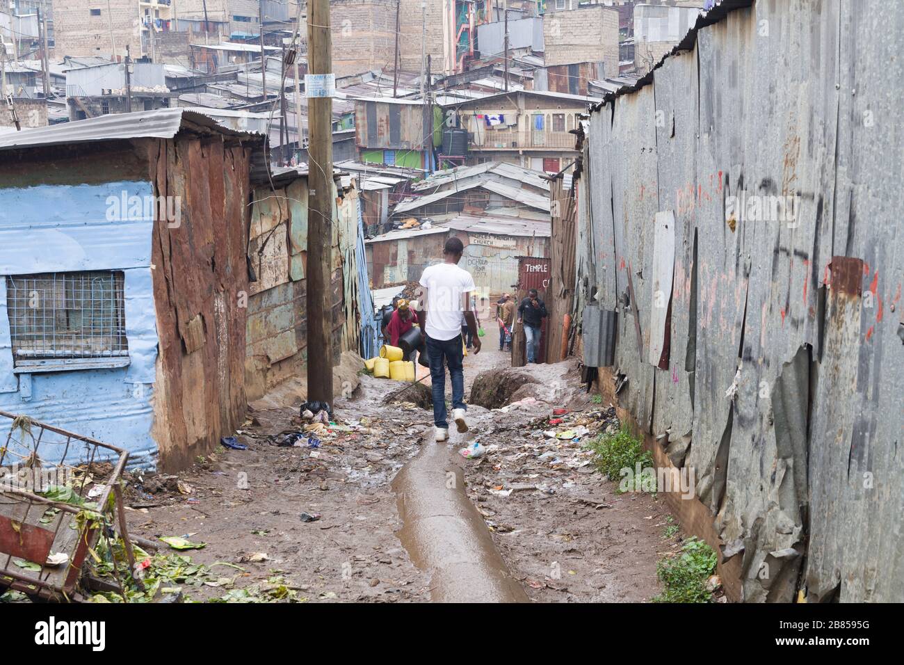 People walking along a rubbish strewn alleyway from a footbridge across ...
