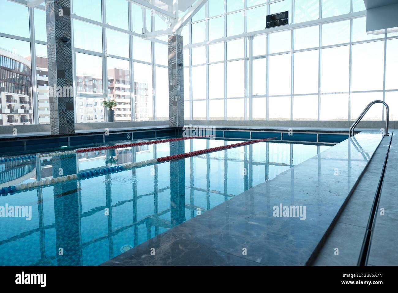 Indoor swimming pool with panoramic windows overlooking city buildings ...