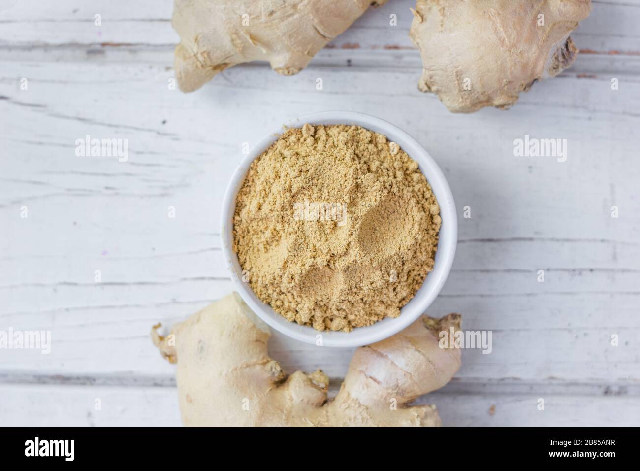 Grounded ginger and ginger root on white wooden surface Stock Photo - Alamy